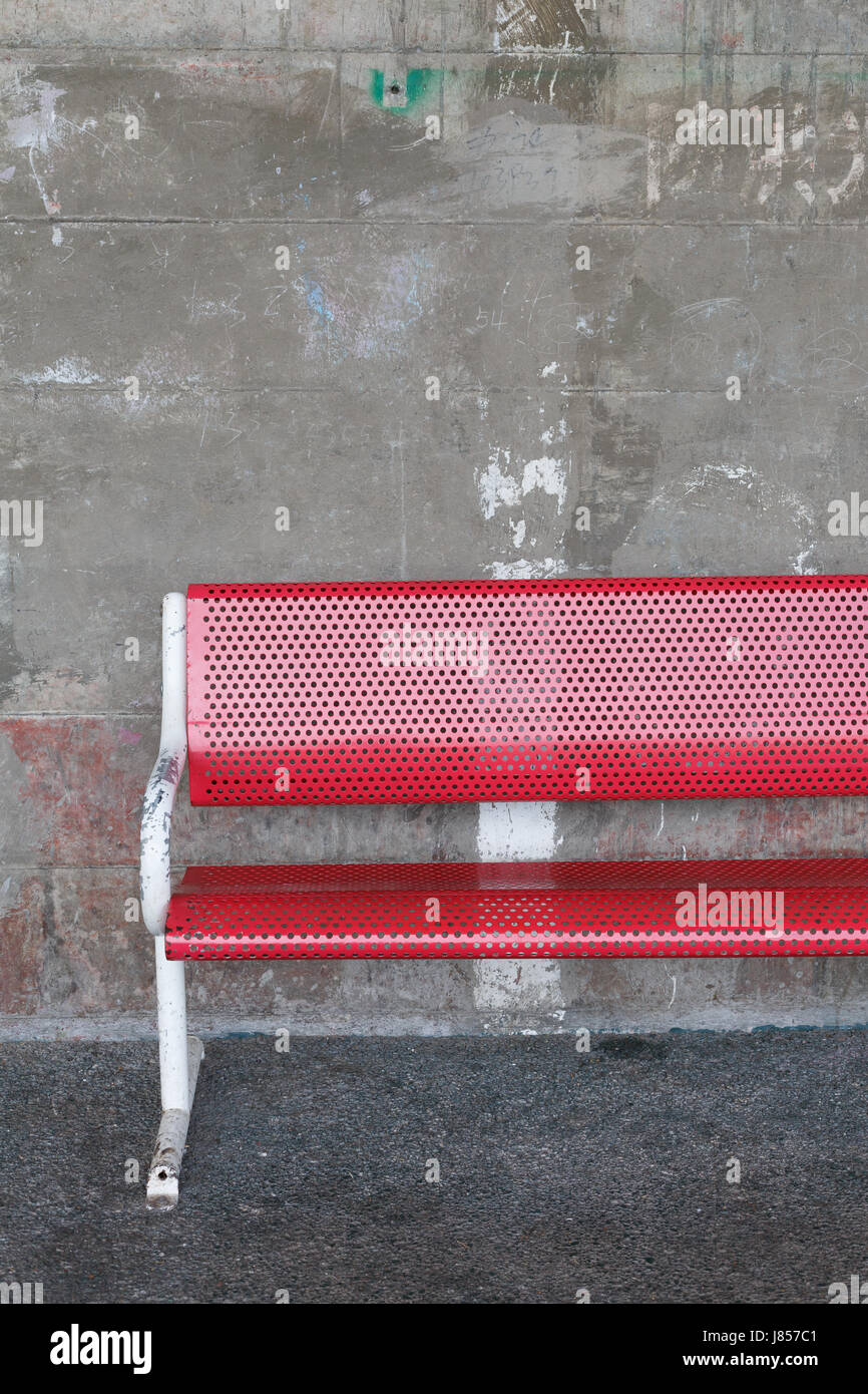 A red public seat is against the concrete wall Stock Photo - Alamy
