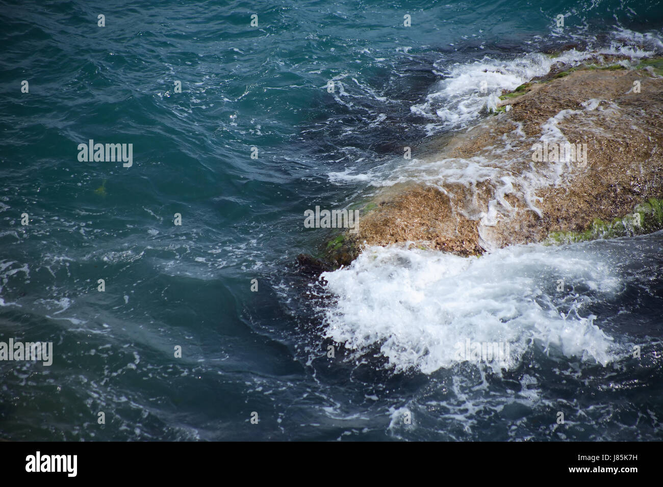 Closeup of big stone in heavy sea with waves Stock Photo - Alamy