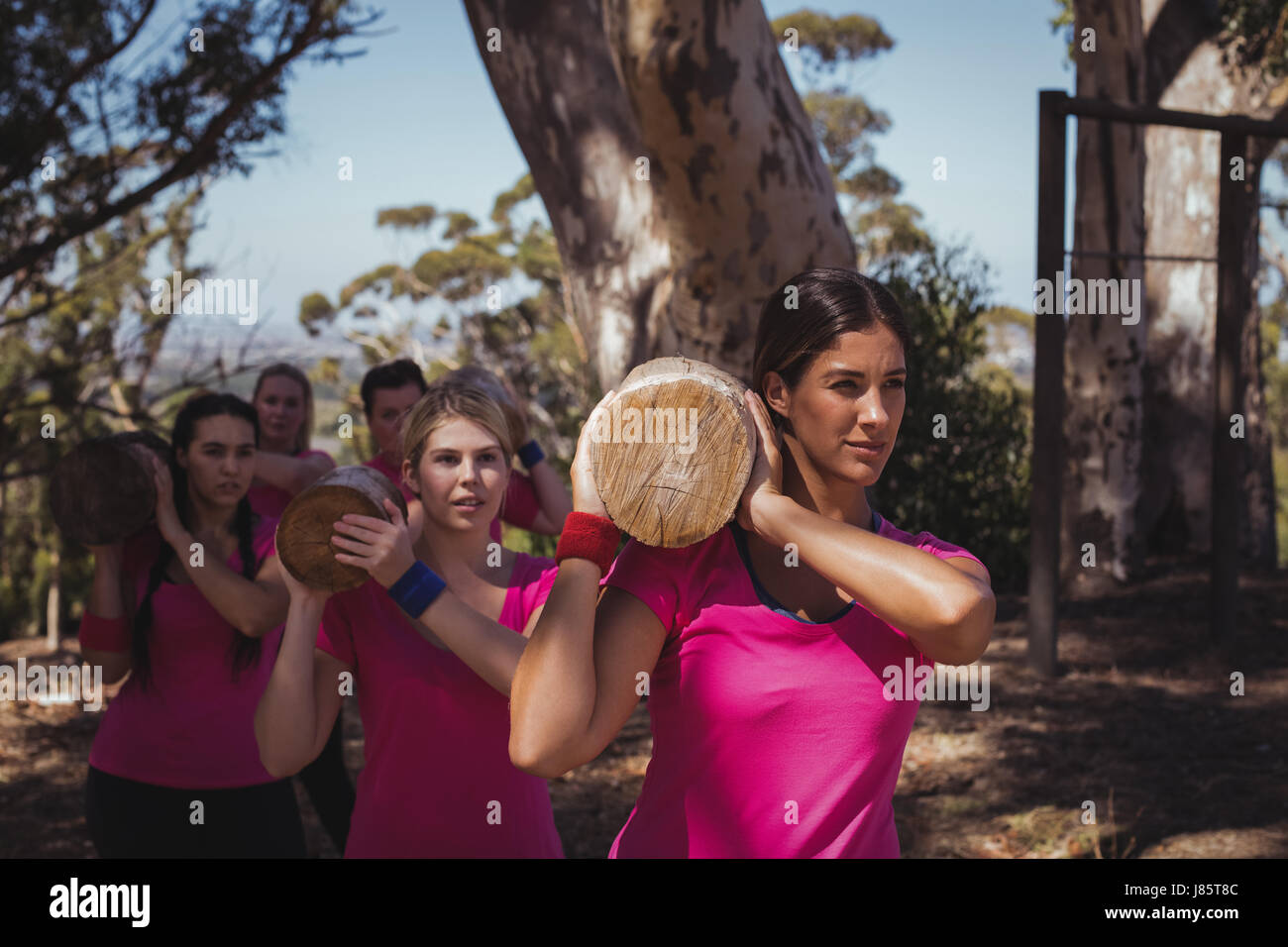 Group of women carrying a heavy wooden log during obstacle course in ...