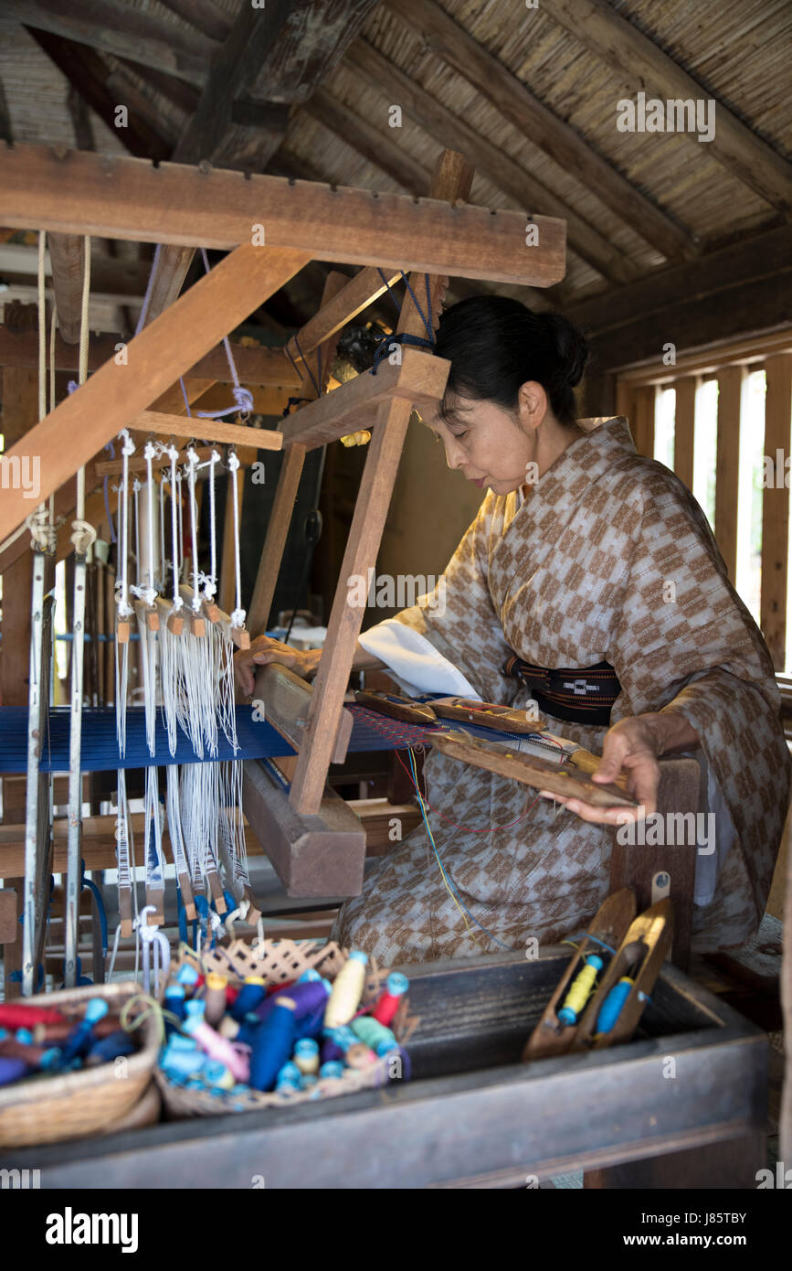 Okinawa woman producing cloth using traditional loom. Ryukyu Mura ...