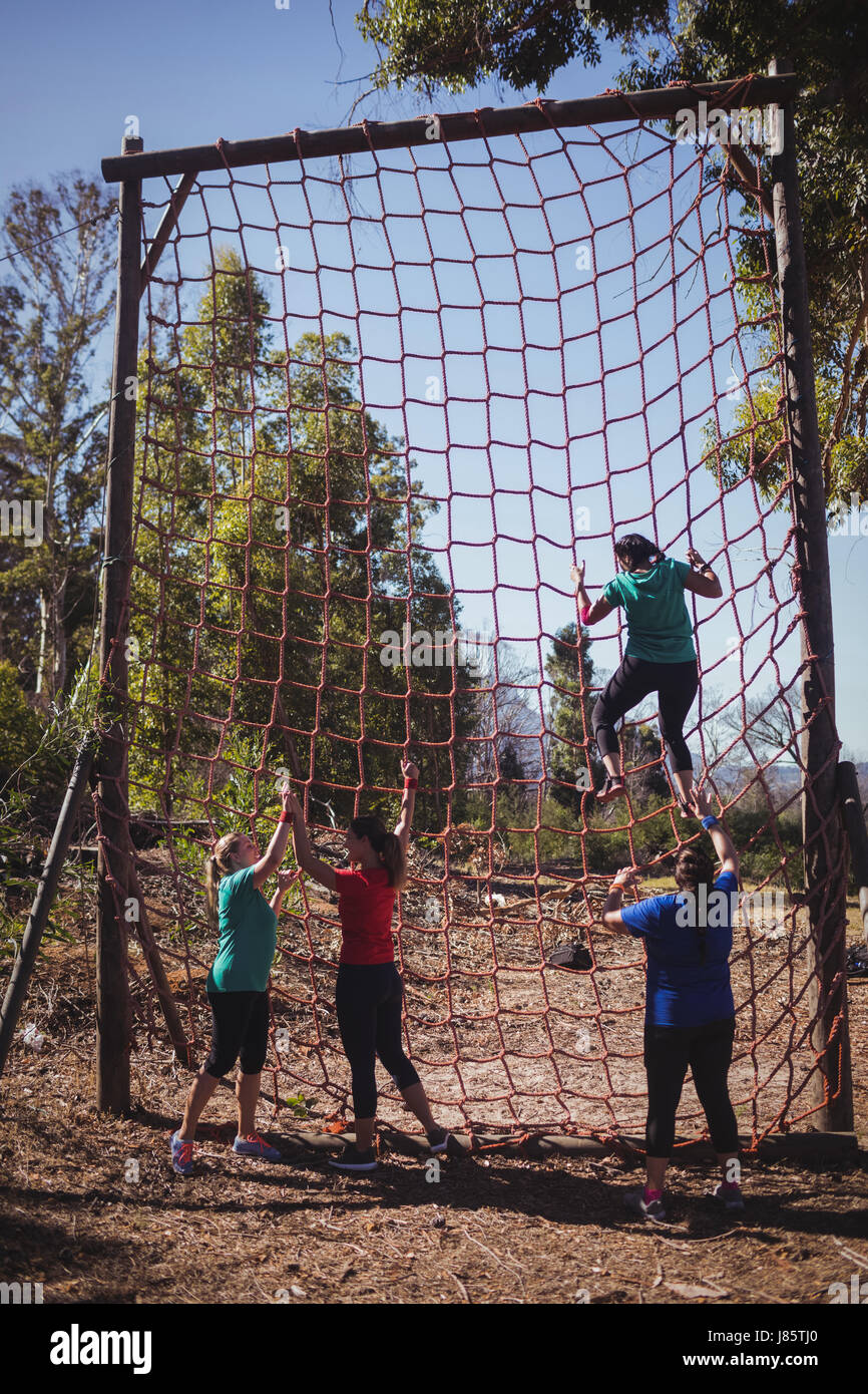 Group of fit woman climbing a net during obstacle course training in ...