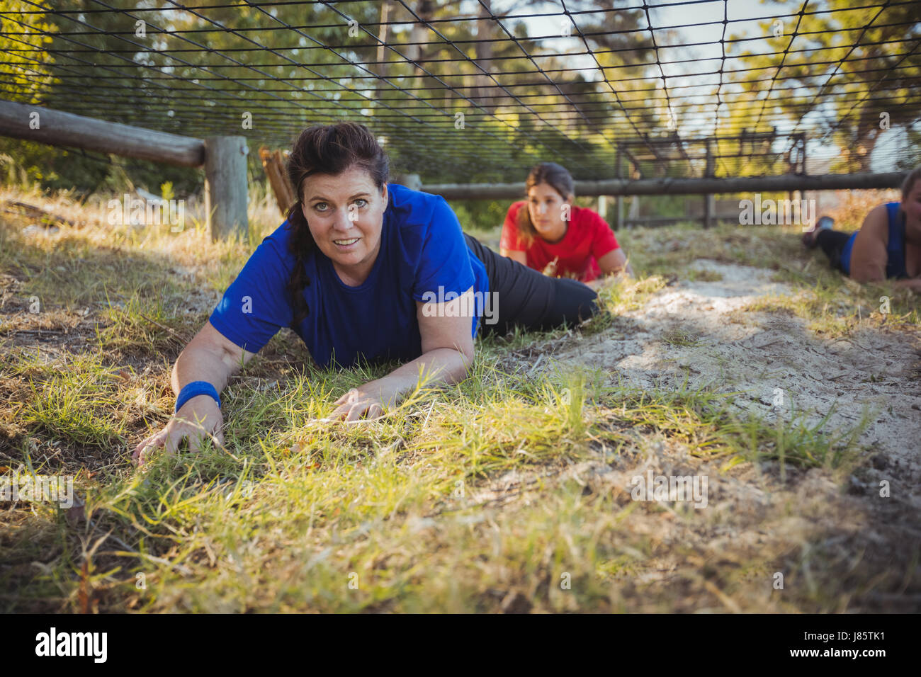 Group of fit women crawling under the net during obstacle course ...