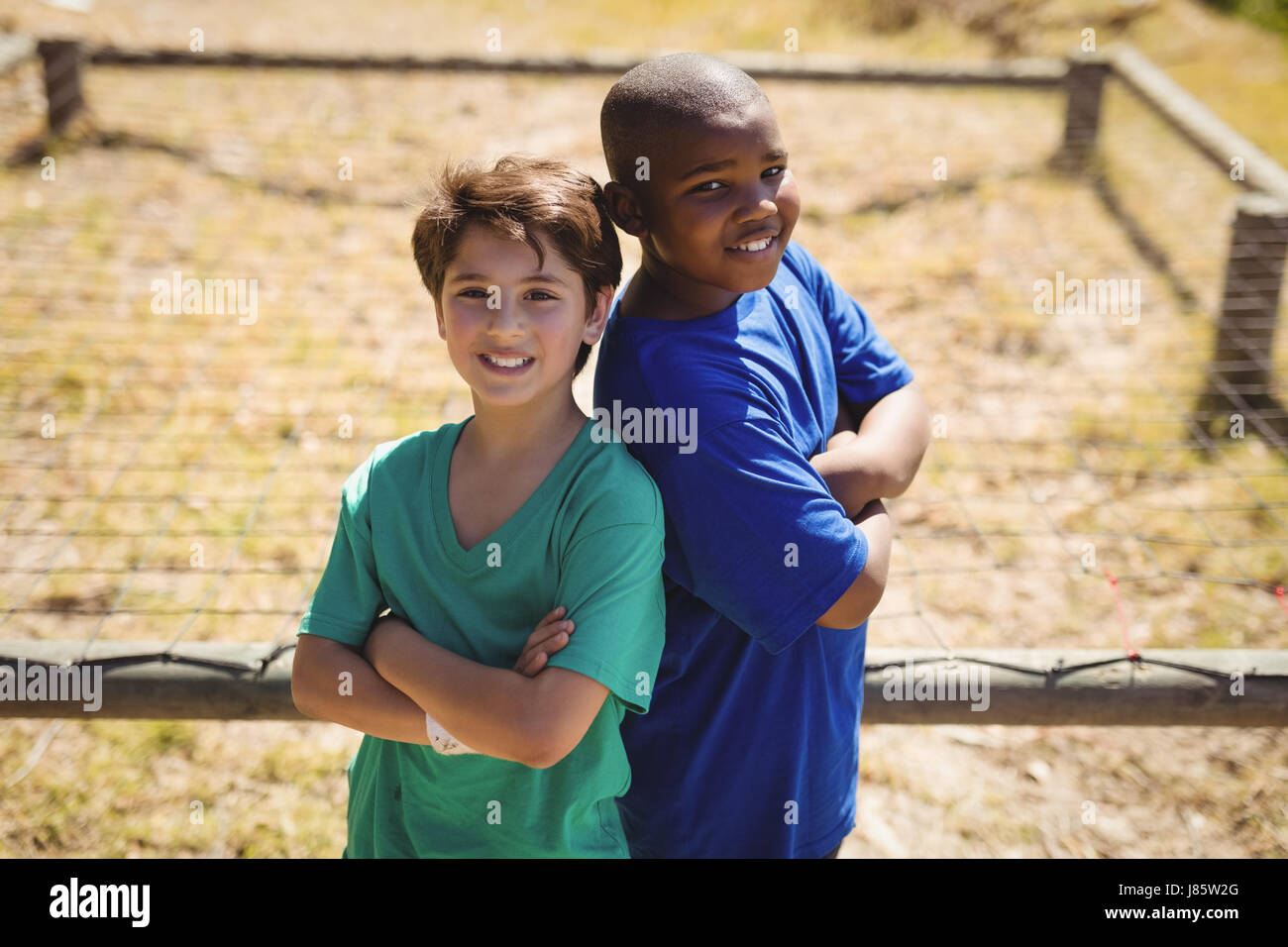 Portrait of happy friends standing with arms crossed during obstacle ...