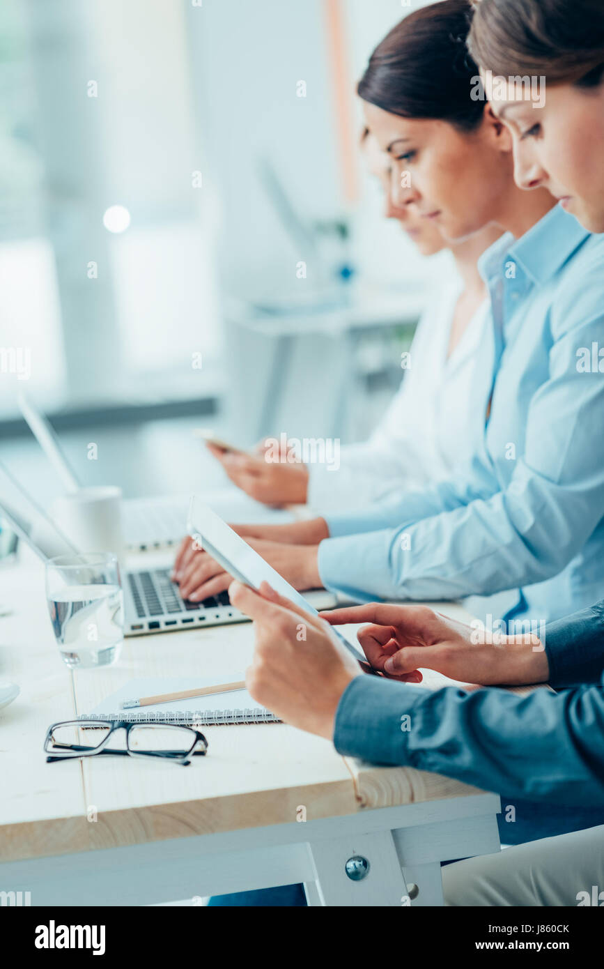 Professional business women working at office desk using laptops and ...