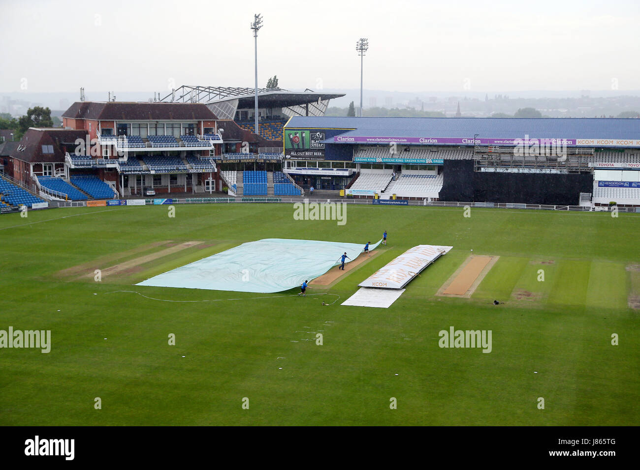 Headingley ground staff cover the field of play as rain falls before ...