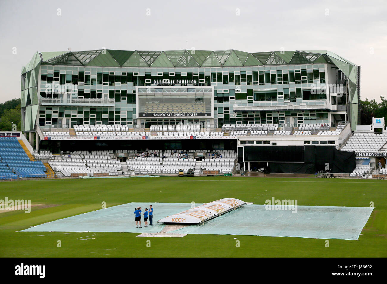 Headingley ground staff cover the field of play as rain falls before ...