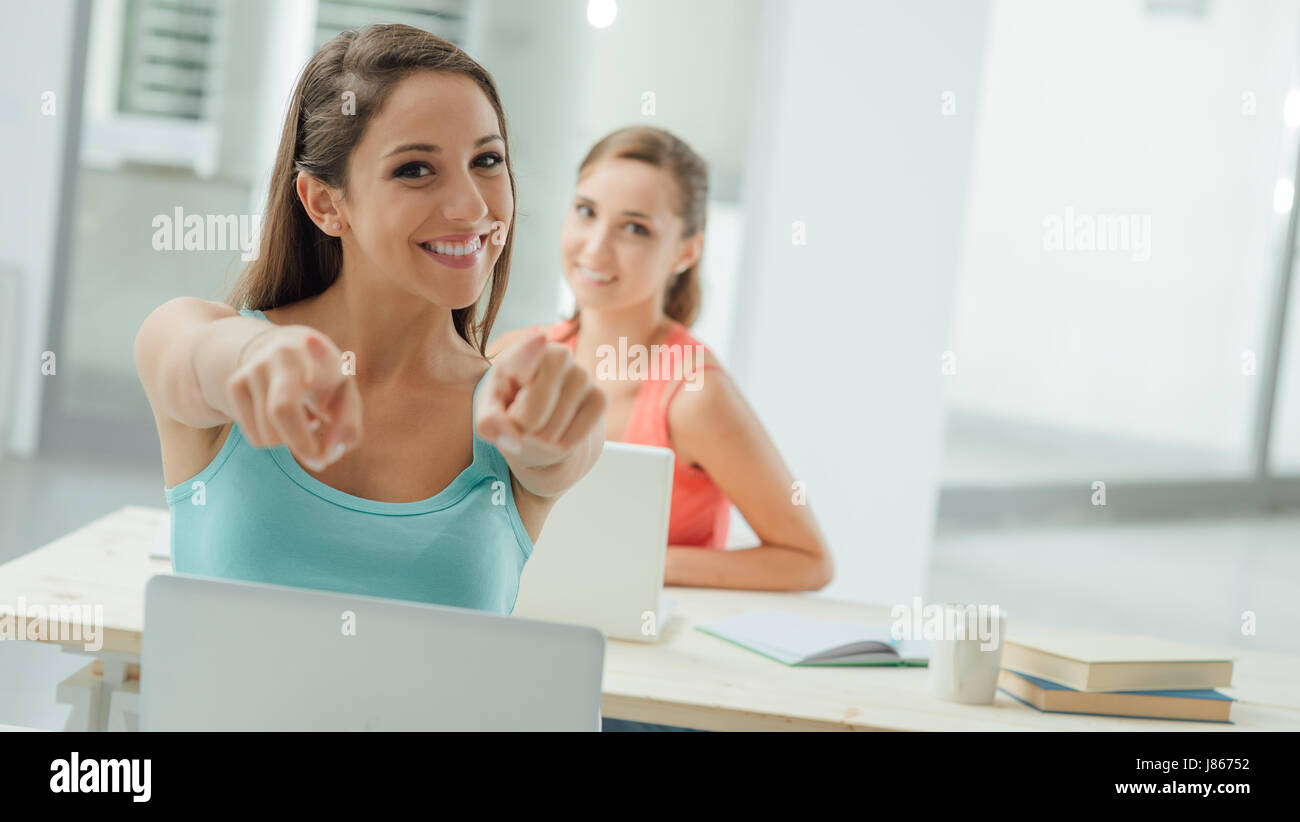 Cheerful student girl pointing at camera and smiling, education and ...