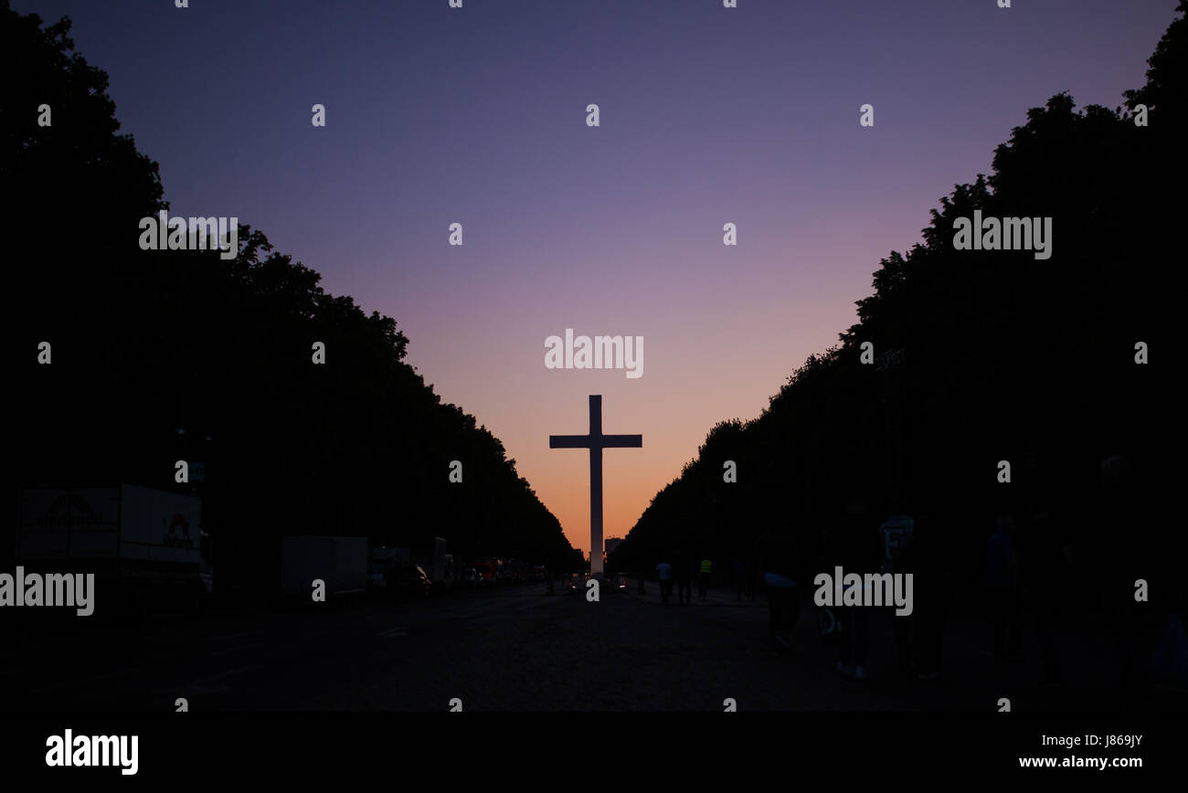 The silhouette of a cross is visible in front of the sunset on the ...