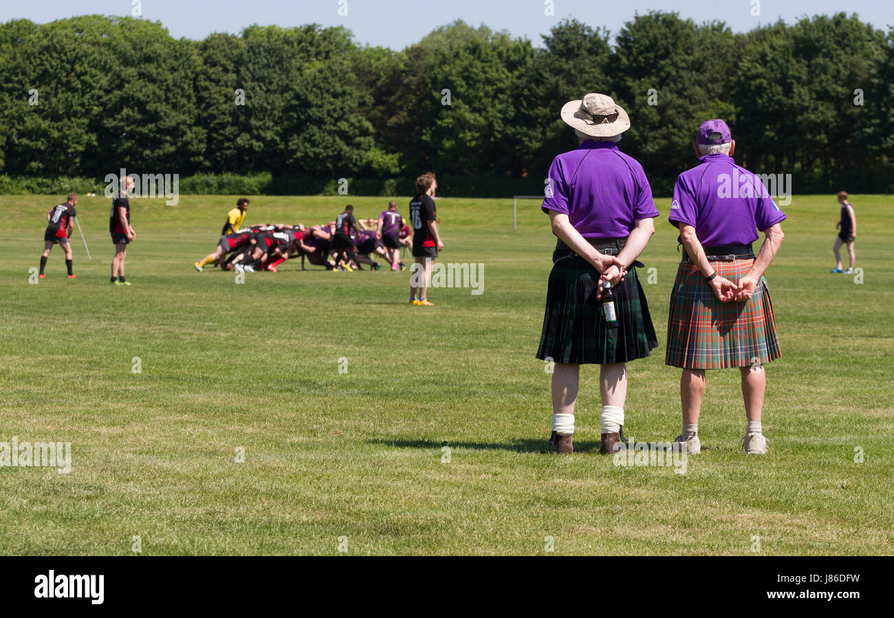 Two Scottish rugby supporters wearing kilts watch match from sidelines ...