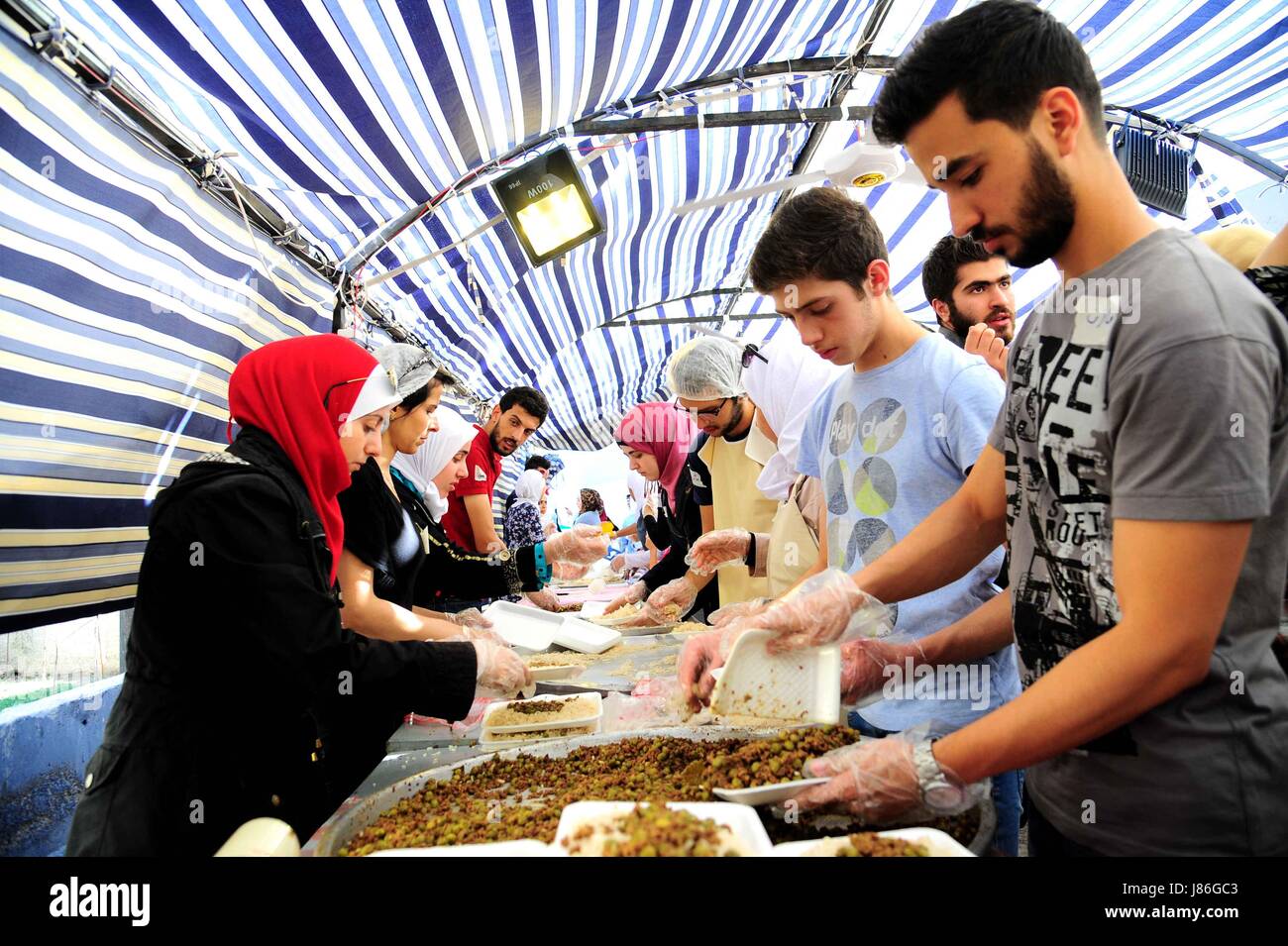 Damascus, Syria. 27th May, 2017. Syrian volunteers cook and pack food ...