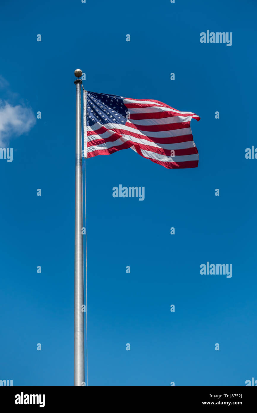 A photo of the American flag on a long pole with blue sky behind Stock ...