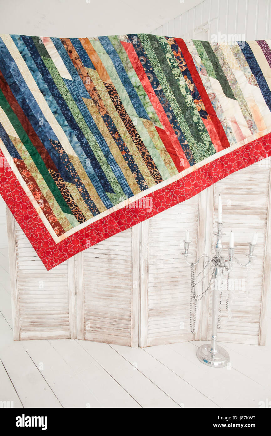 Patchwork quilt hangs on a wooden screen. Part of patchwork quilt in a ...