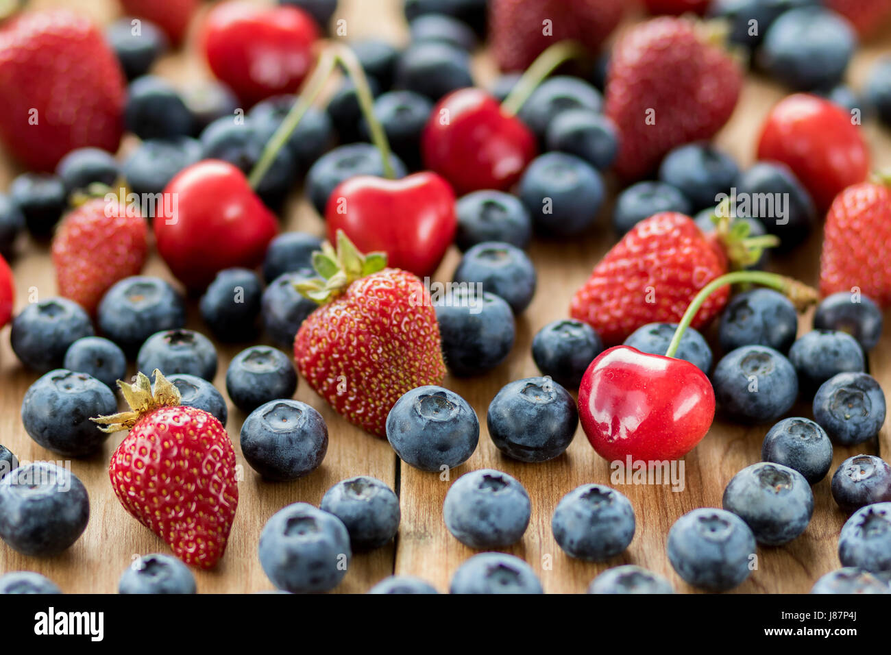 Strawberries, cherries and blueberry on wooden table, background Stock ...