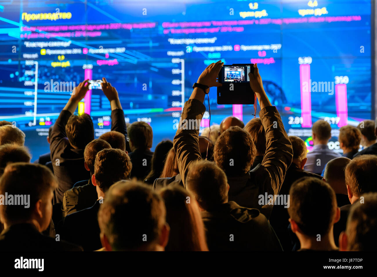 Man takes a picture of the presentation at the conference hall using ...