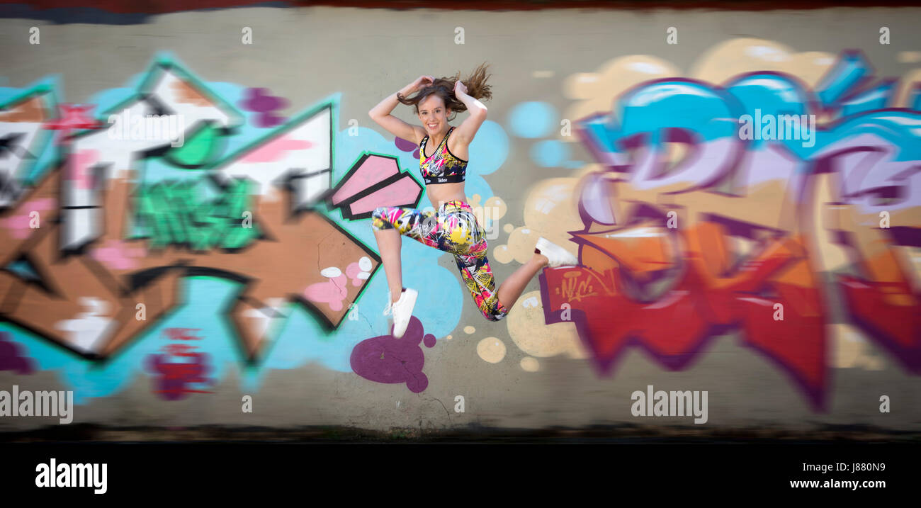woman running and jumping, keeping fit, wearing colourful sportswear ...