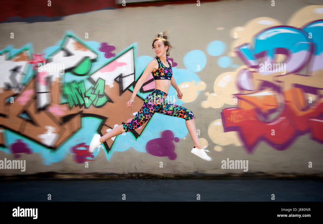 woman running and jumping, keeping fit, wearing colourful sportswear ...