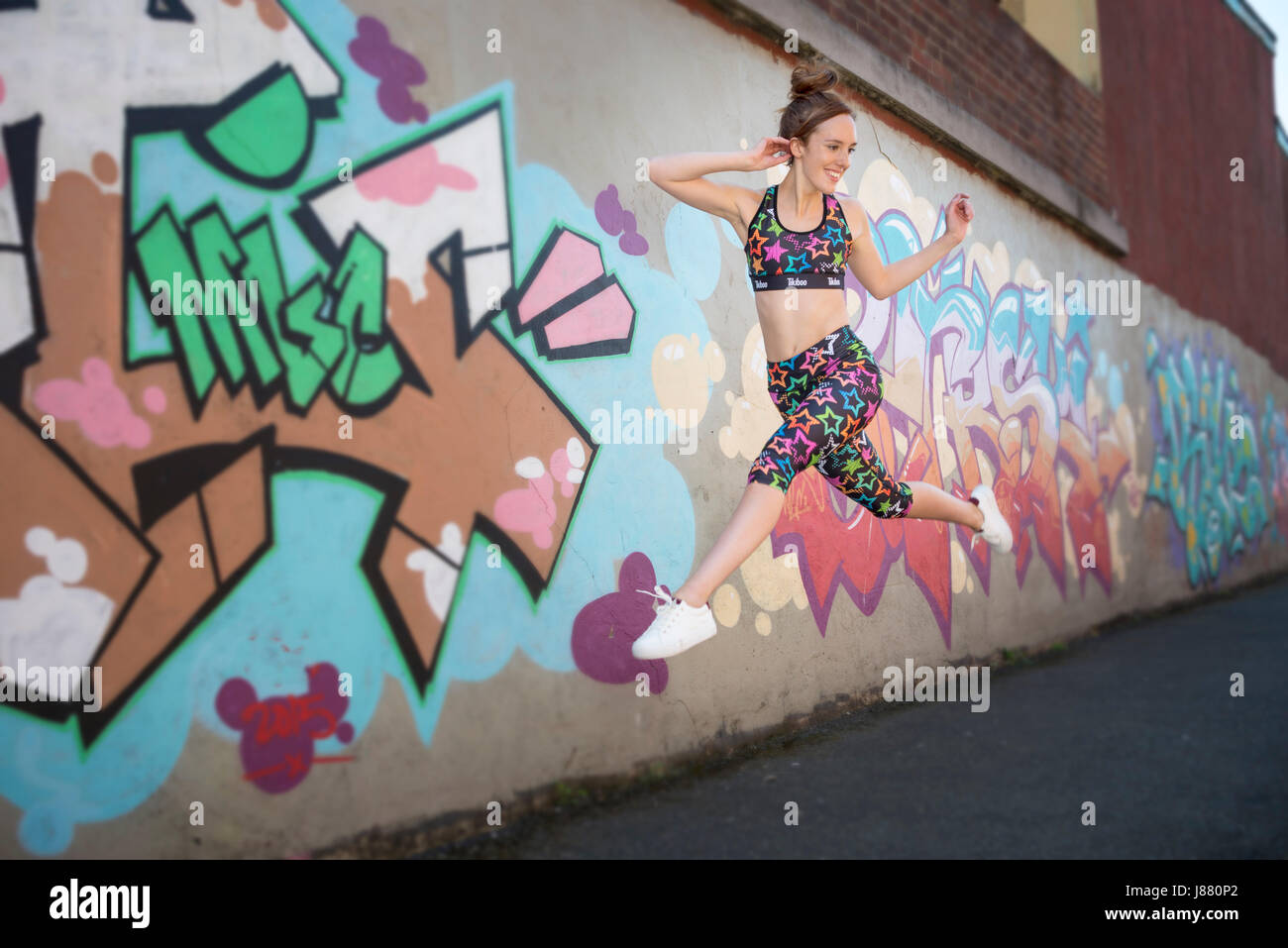 woman running and jumping, keeping fit, wearing colourful sportswear ...