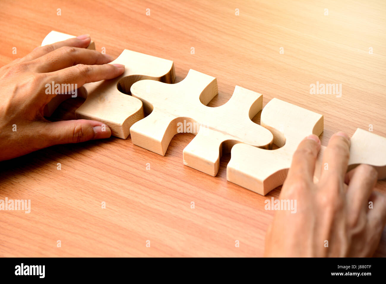 hand holding wood jigsaw piece texture pattern on wood table background ...
