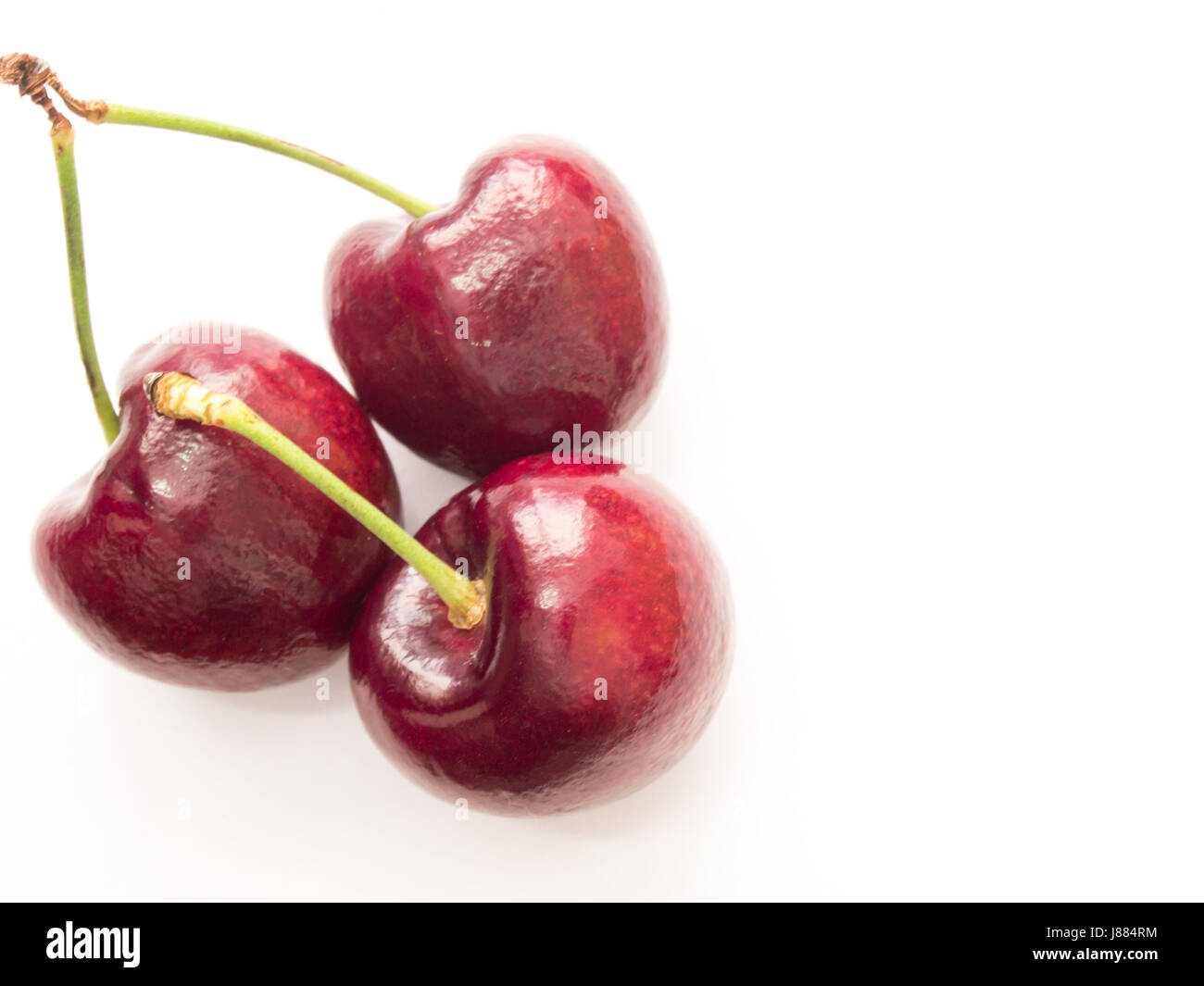 Three red cherry on white background Stock Photo - Alamy