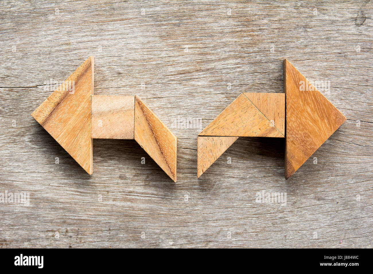 Tangram puzzle as two way arrow shape on wooden background Stock Photo ...