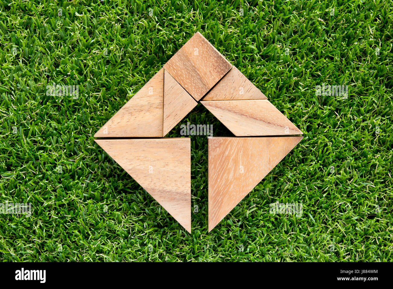 Wooden tangram puzzle as arrow in square shape on green grass ...