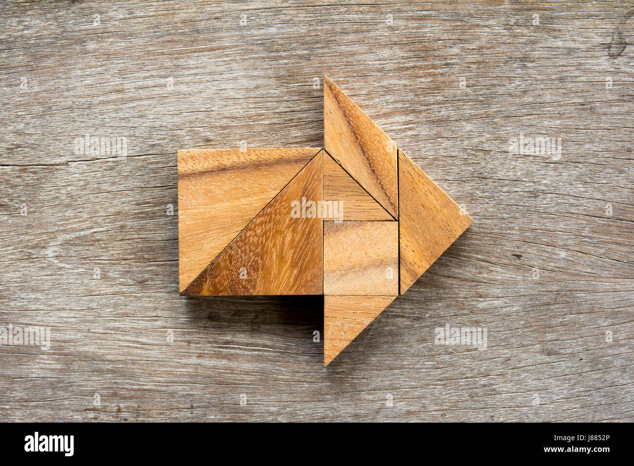 Tangram puzzle in arrow shape on wooden background Stock Photo - Alamy