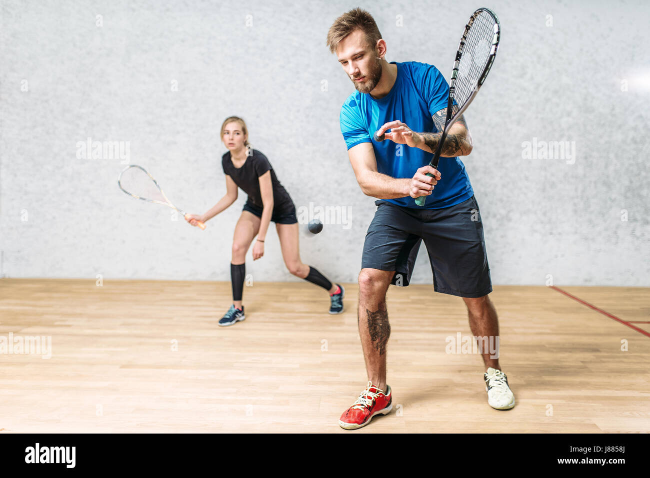 Young couple with squash rackets, indoor training club. Active sport ...