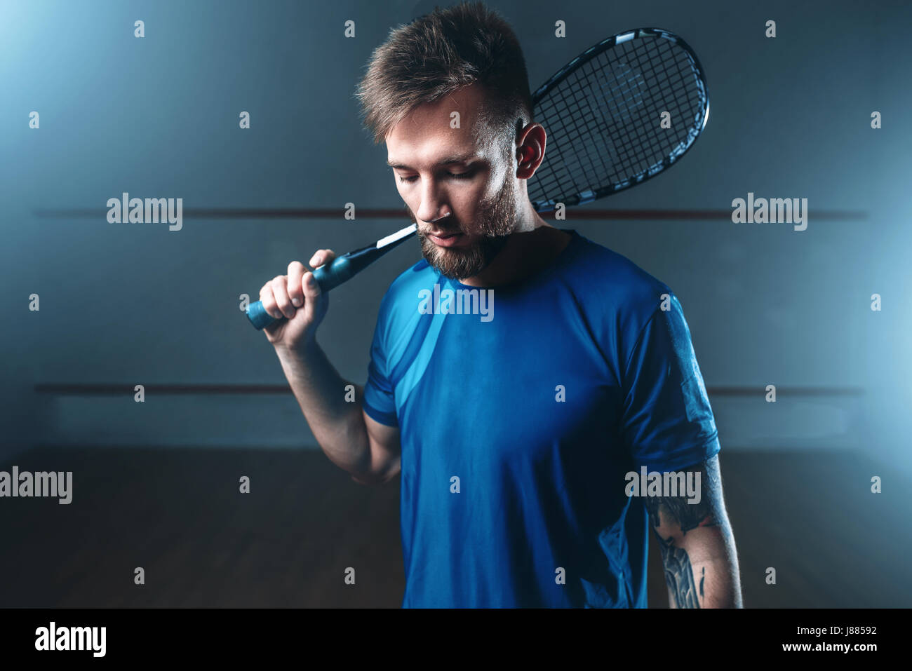 Male squash player with racket, indoor training court on background ...