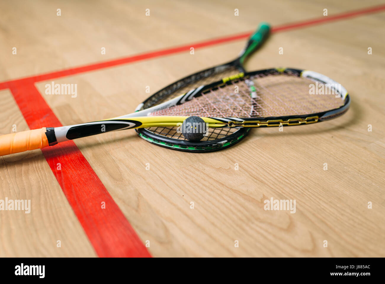 Squash game equipment closeup view. Rackets and ball on the floor in ...