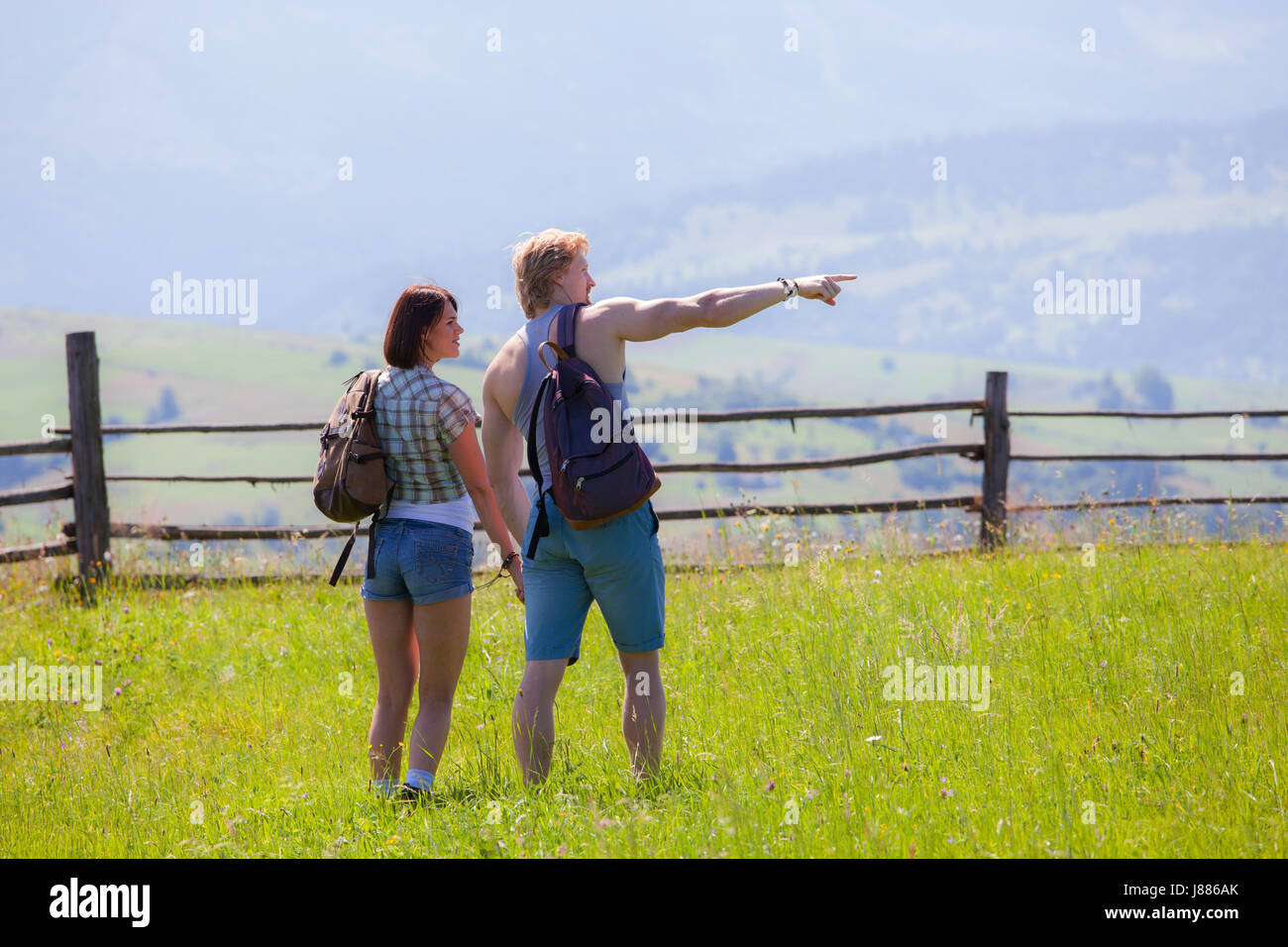 Couple walking together at the summer meadow and looking around ...