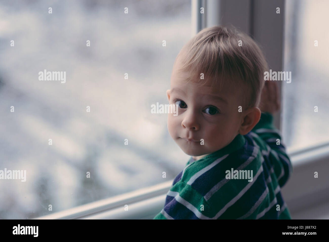 baby looking at the snow over the window Stock Photo - Alamy