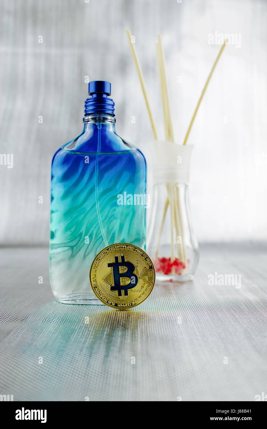 Cryptocurrency physical gold bitcoin coin near fragrance in blue bottle ...