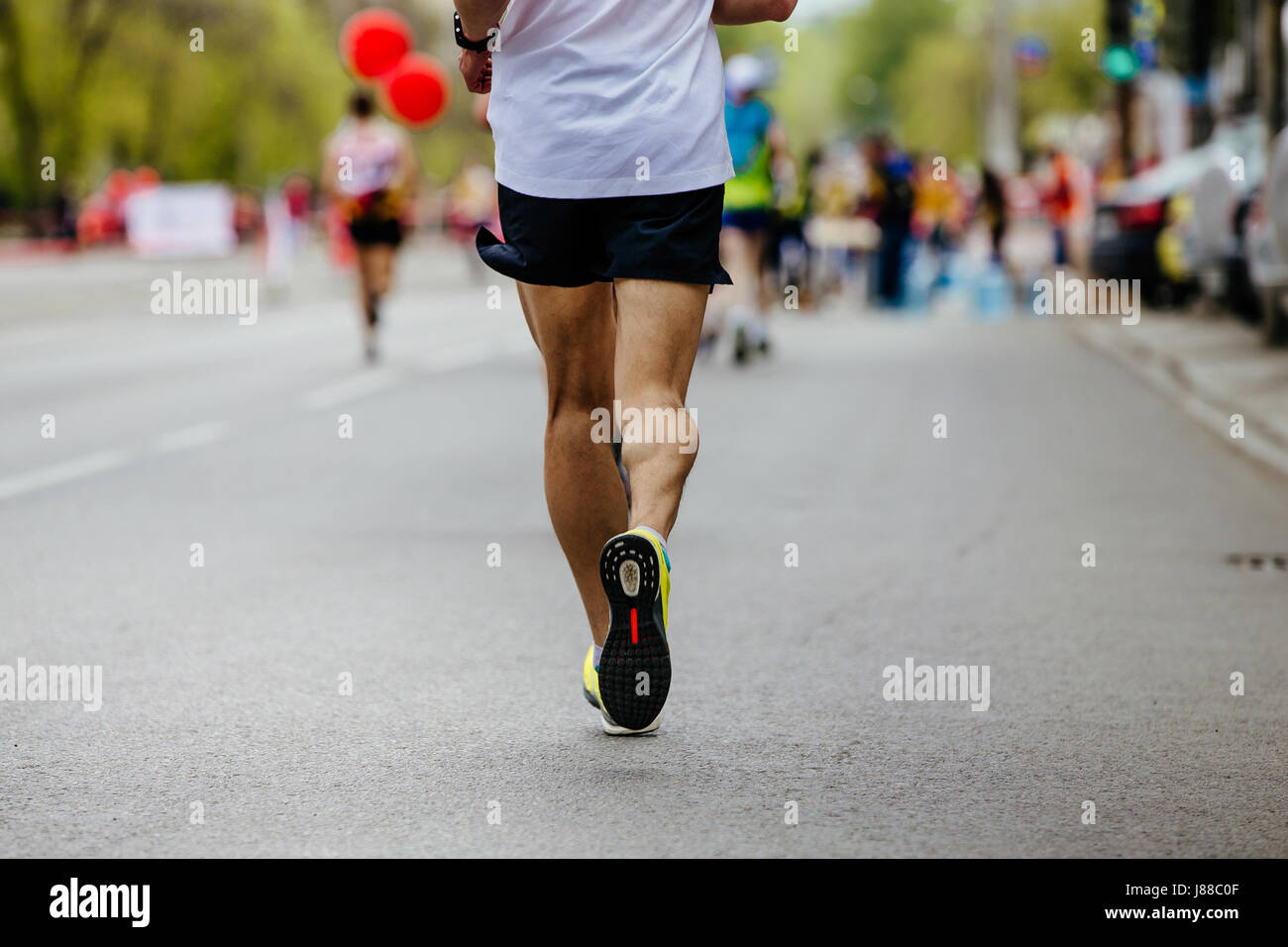 back male runner running streets of the city on background of runners ...
