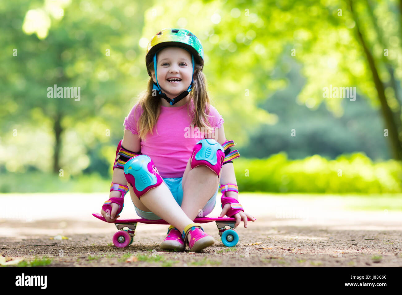 Child riding skateboard in summer park. Little girl learning to ride ...