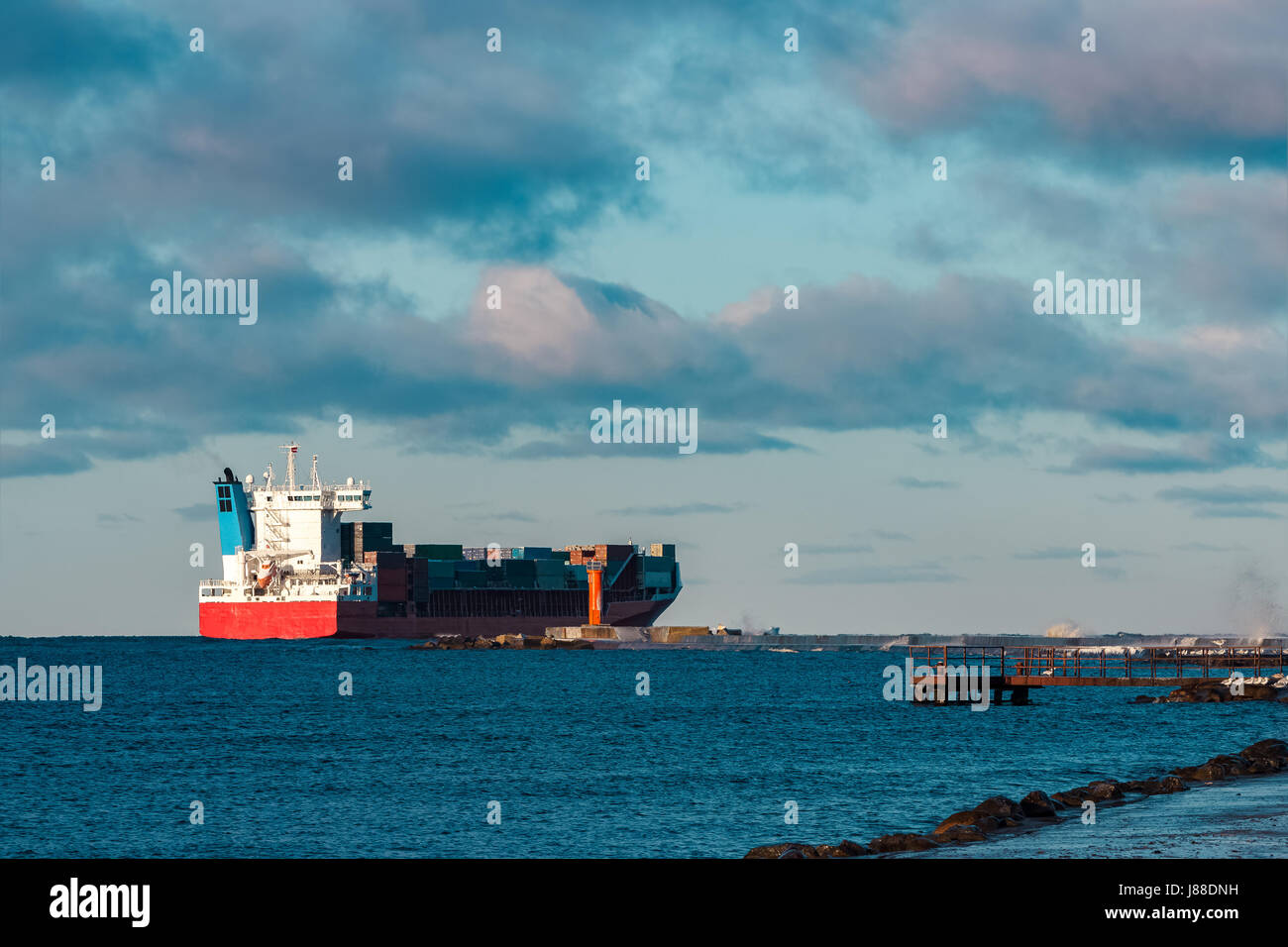 Full red container ship moving in still water Stock Photo - Alamy