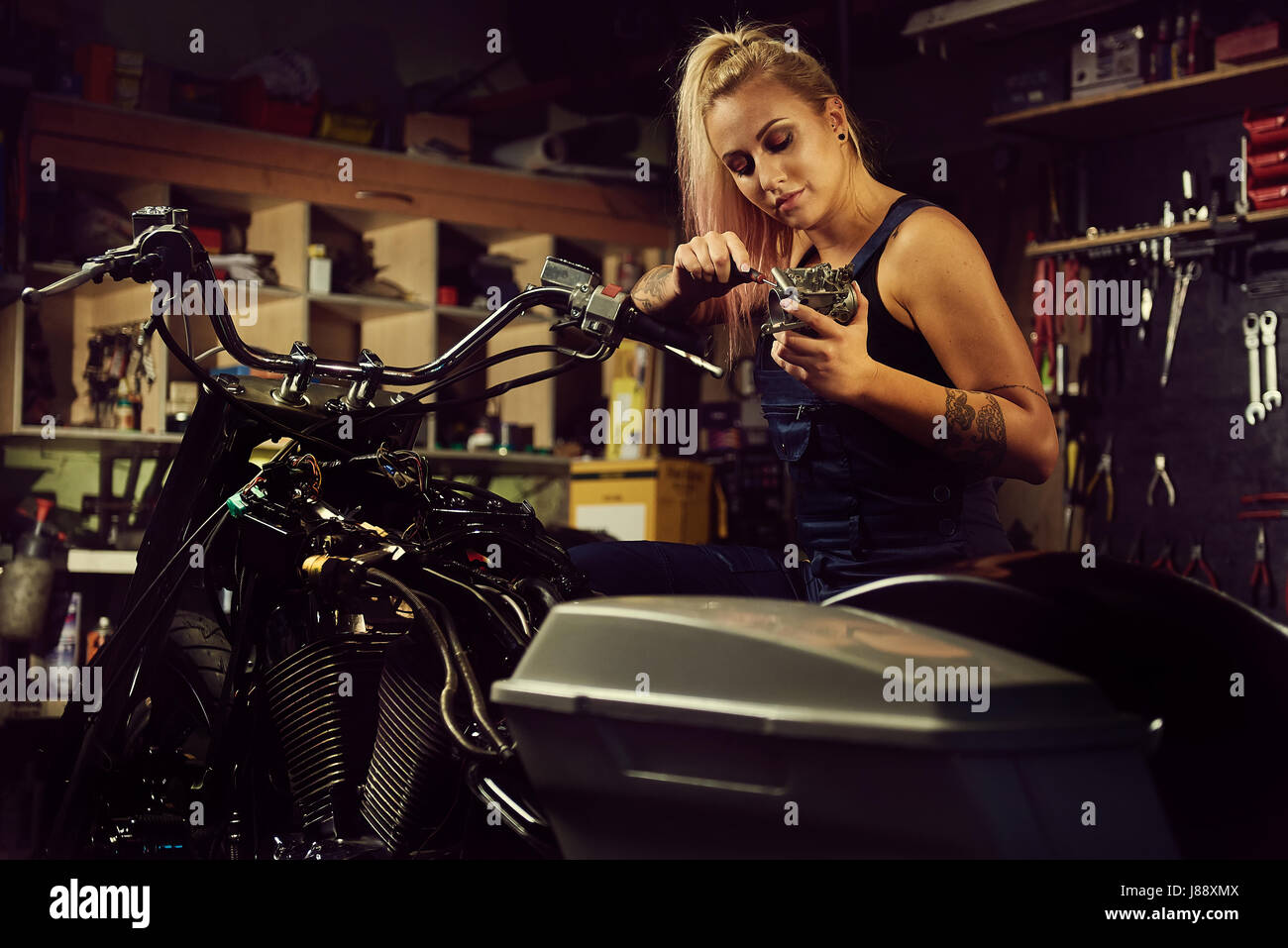 Blond woman mechanic repairing a motorcycle in a workshop Stock Photo ...