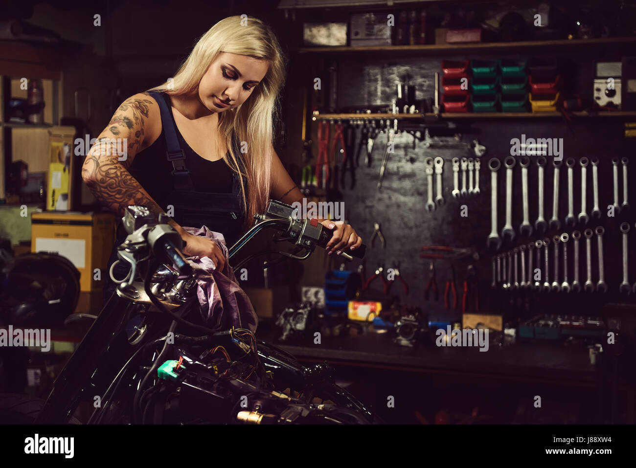 Blond woman mechanic working in a motorcycle workshop Stock Photo - Alamy