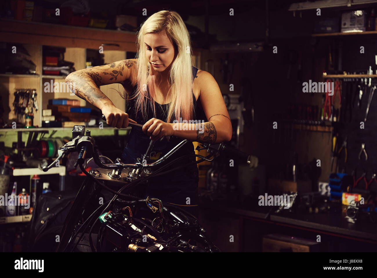 Blond woman mechanic repairing a motorcycle in a workshop Stock Photo ...