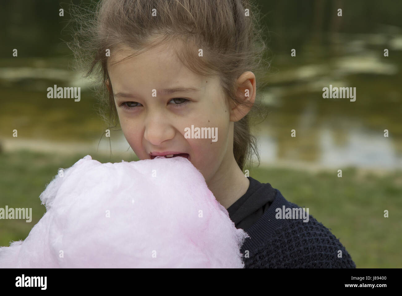 Adorable little girl eating candy-floss outdoors at summer Stock Photo ...