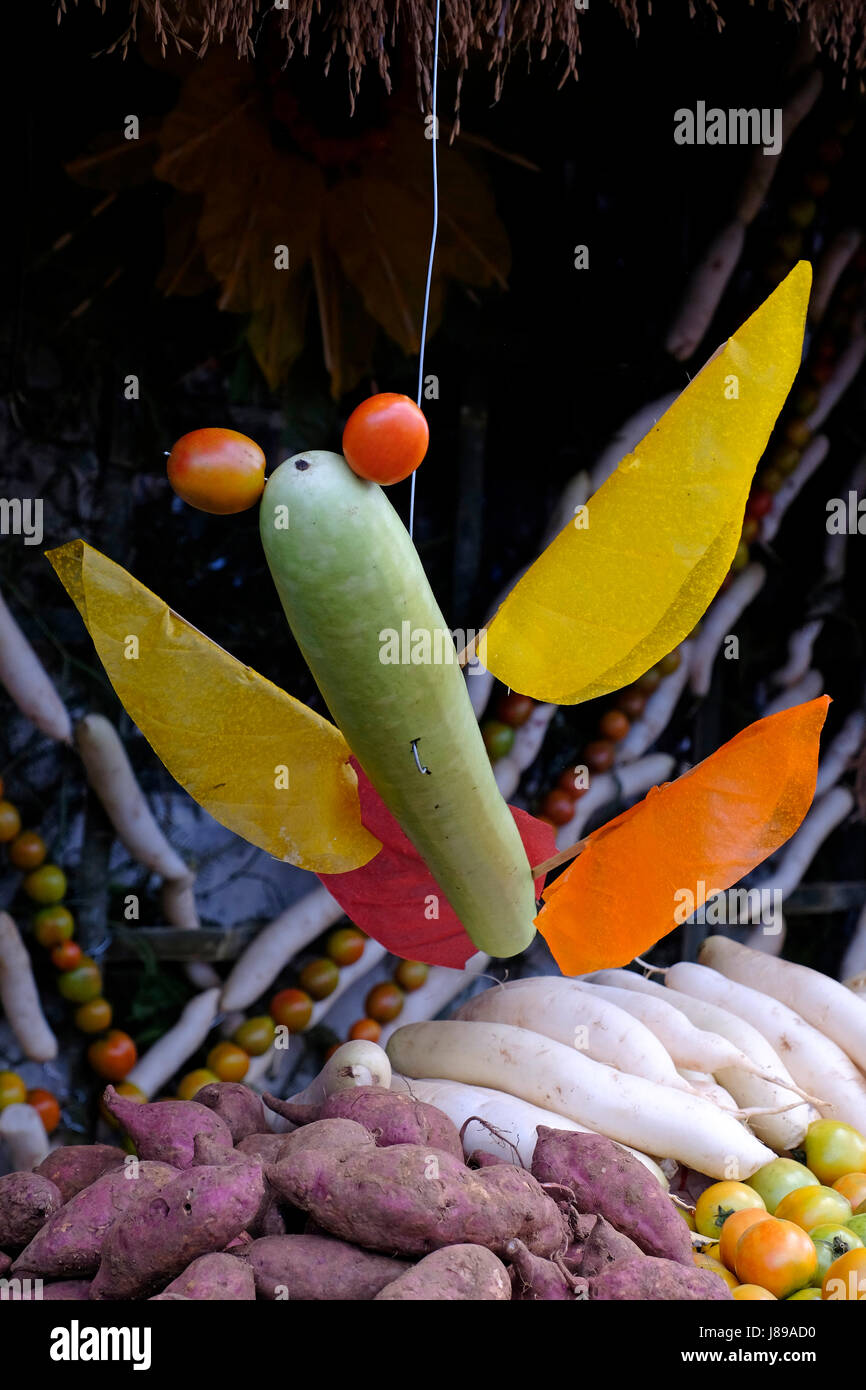 A large green gourd and tomatoes form the body of a decorative piece in ...