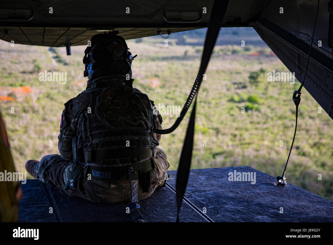 A British MK3 Merlin Crew Chief, observes the training area off the ...