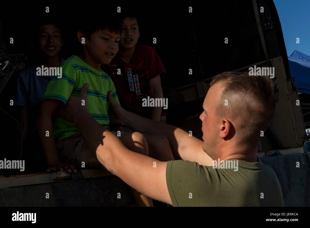 Marine Corps personnel assist children exiting a tactical vehicle ...