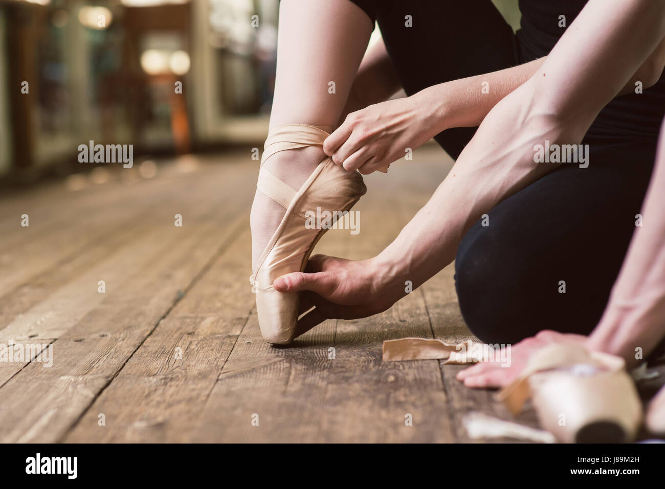 Young ballerina or dancer girl putting on her ballet shoes on the ...