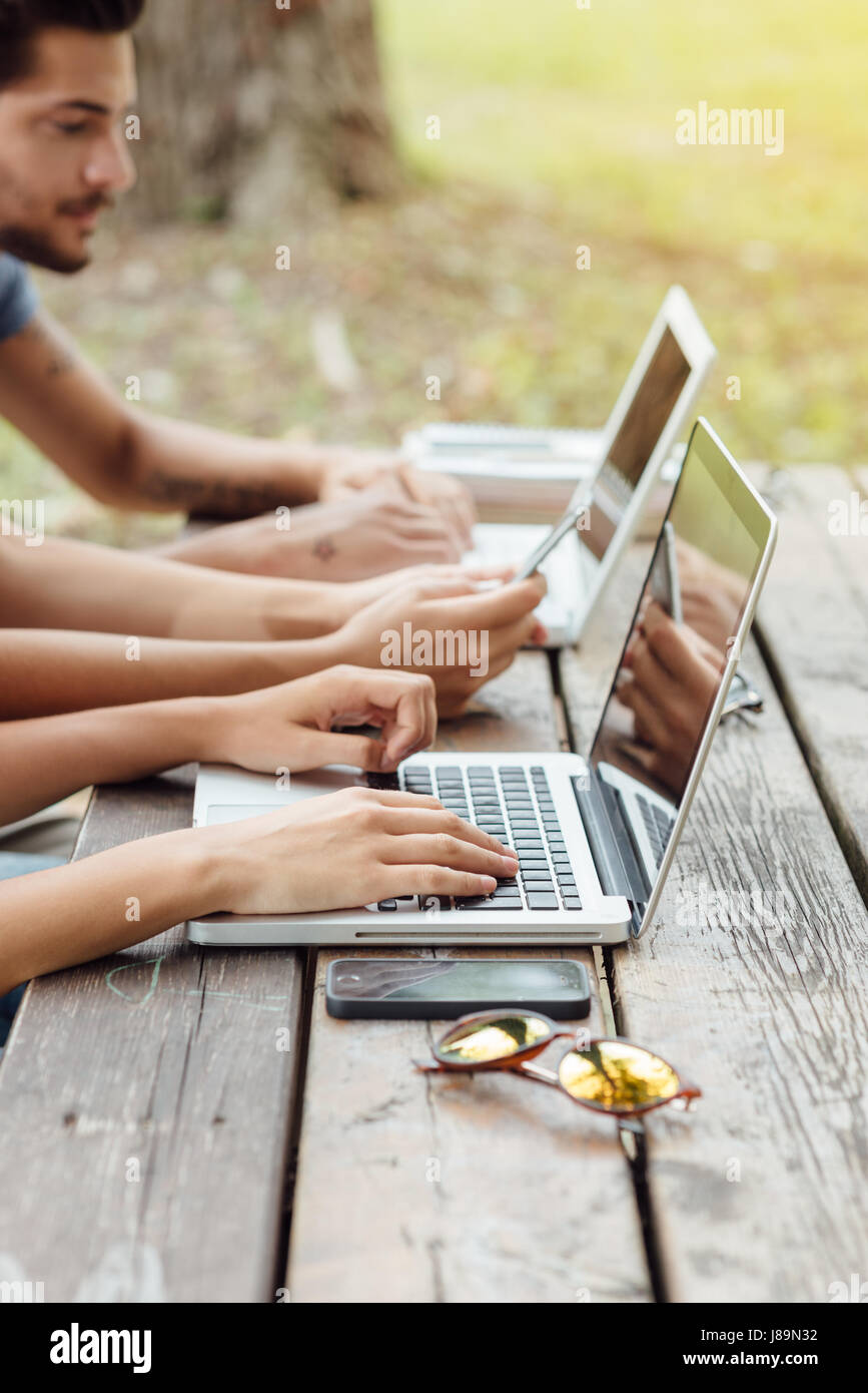 Group of students using laptops outdoors, hands close up, education and ...