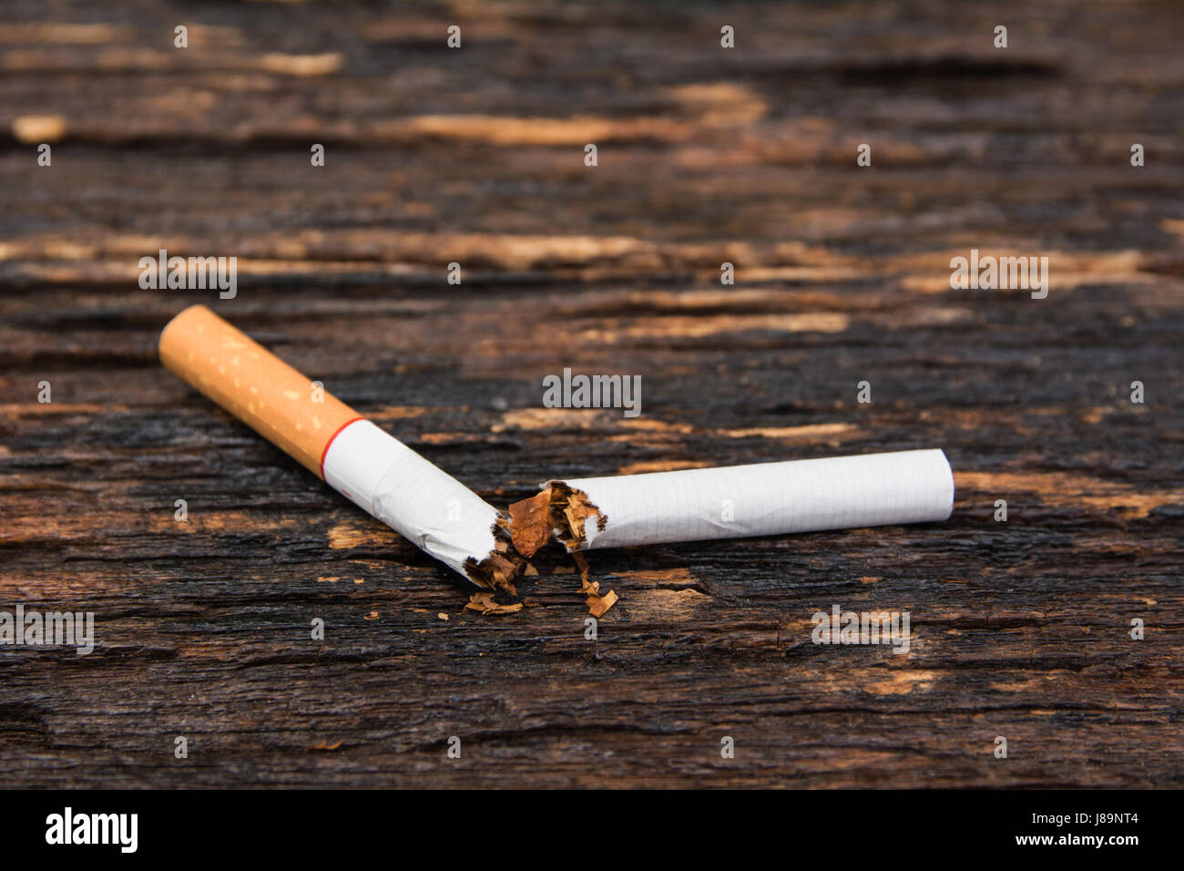 Cigarette divided into two parts on wooden background Stock Photo - Alamy