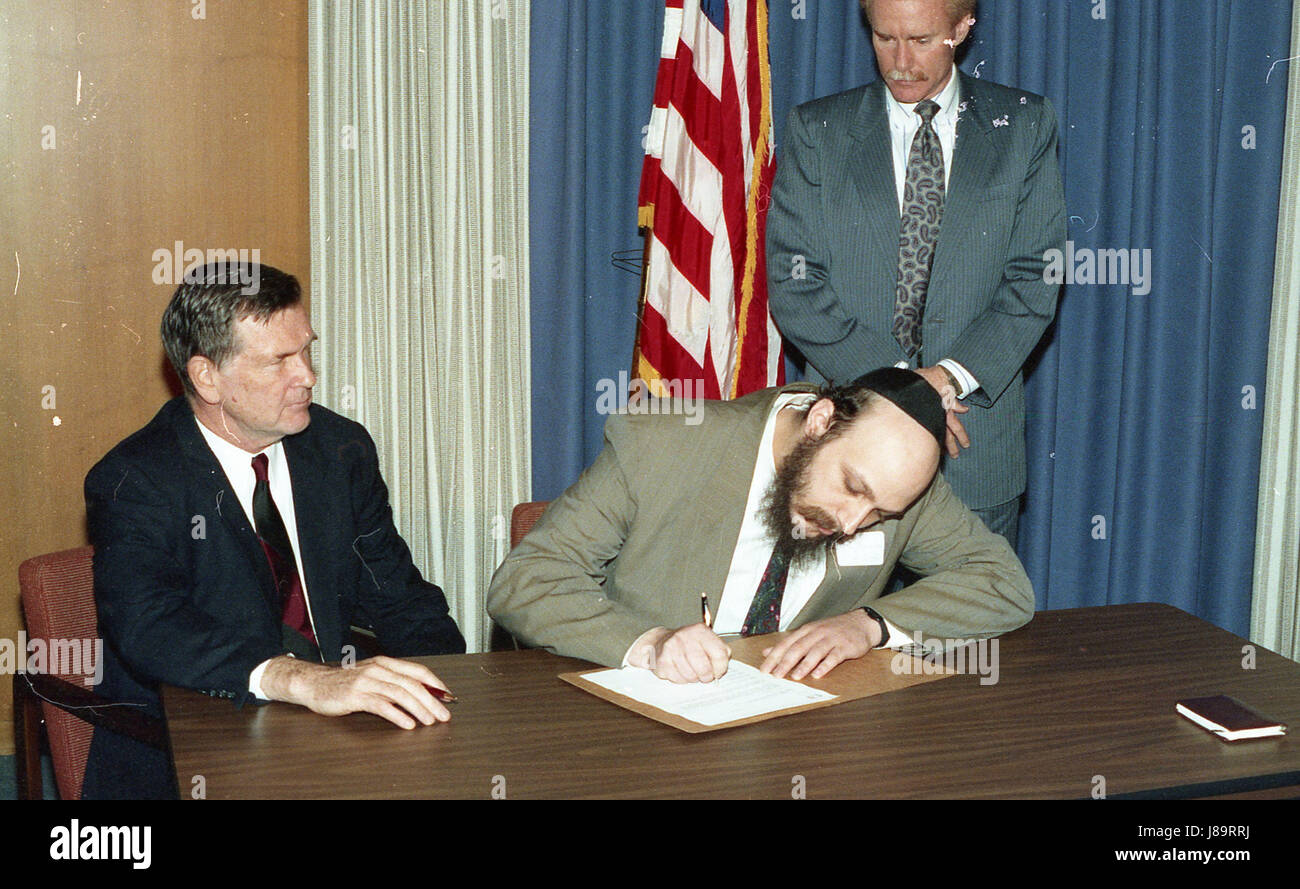 Several men sit and sign documents, completing administrative ...