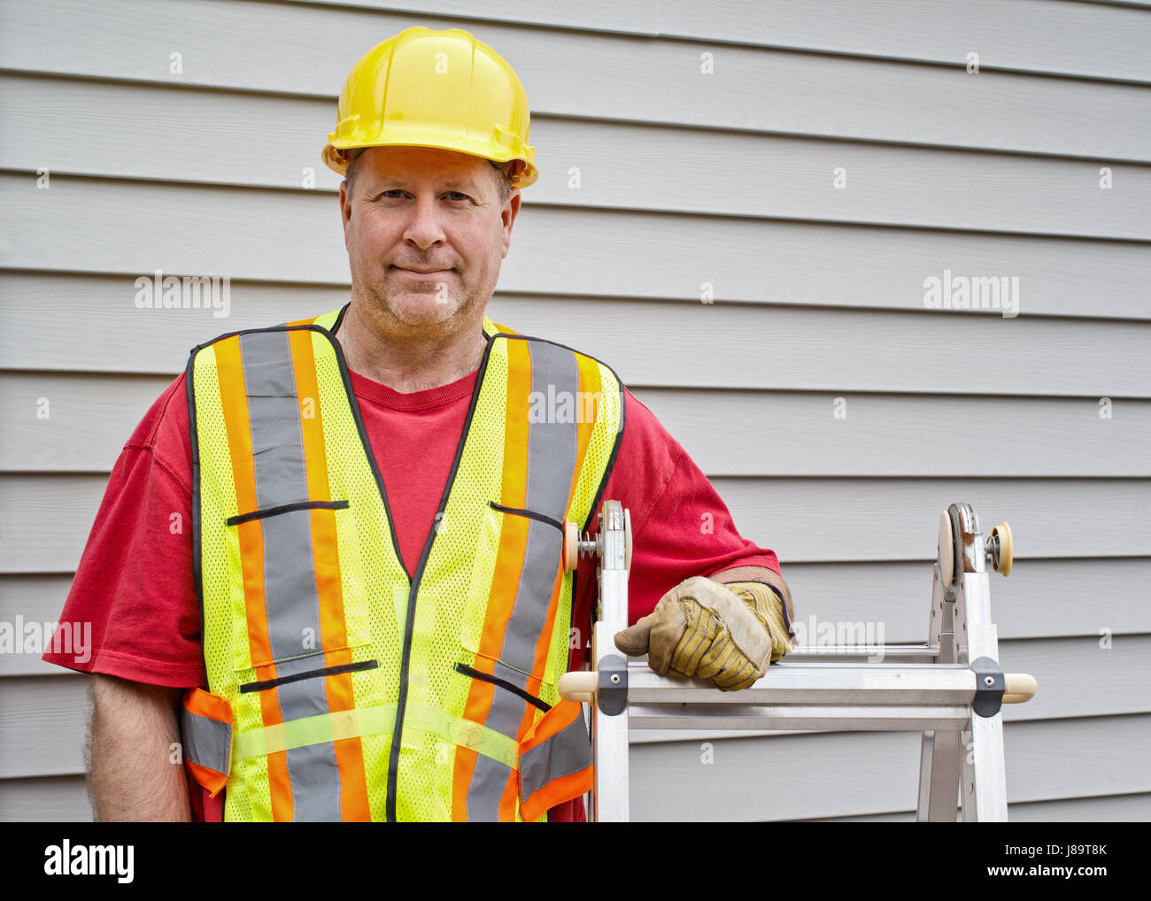 Male construction worker standing beside step ladder Stock Photo - Alamy