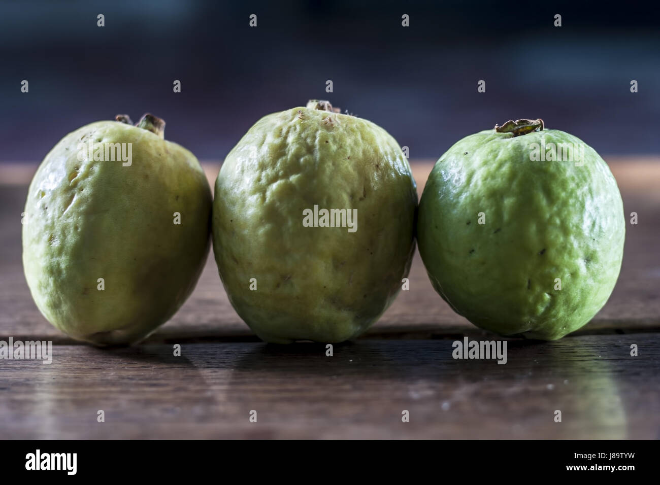 Three Psidium guajava common guava, raw on a wooden surface Stock Photo ...