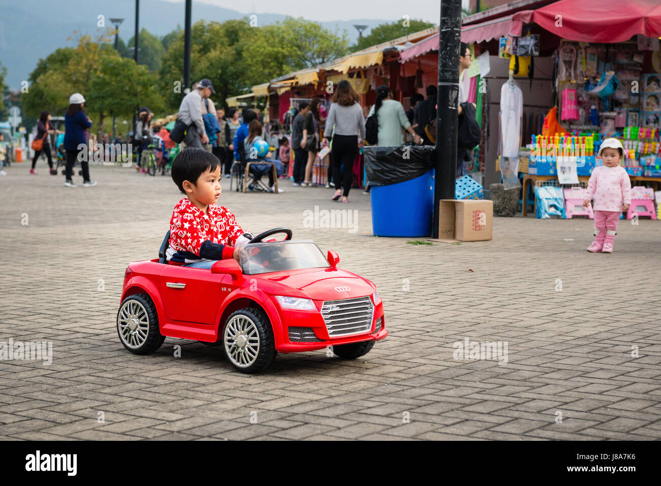 Chinese boy driving red toy car Stock Photo - Alamy