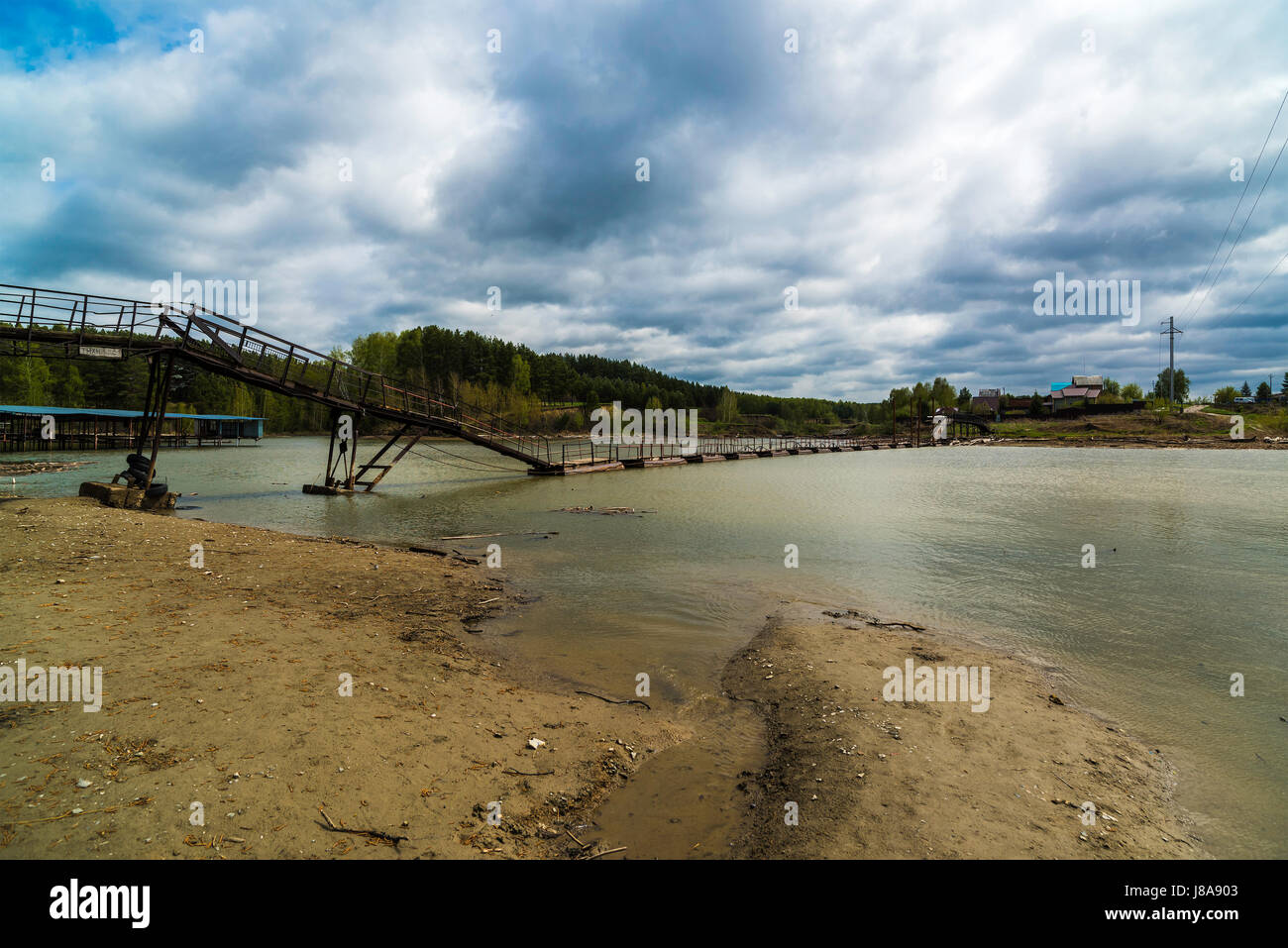 An old pontoon bridge across the river. Russia, Siberia, the Razdelnaya ...